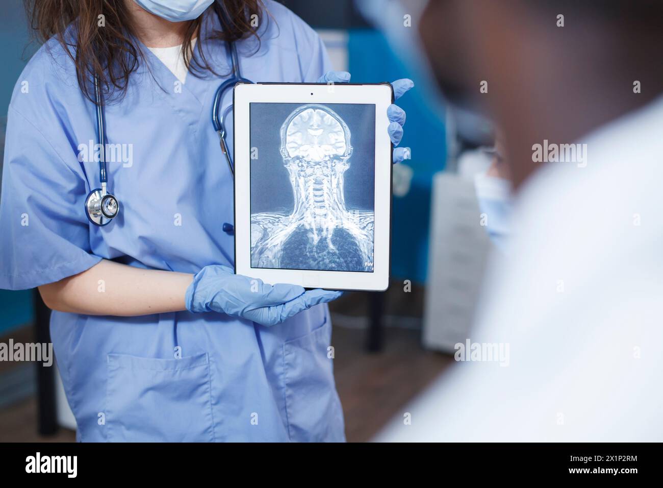 In medical office, doctor uses tablet to analyze a scan of a patient's ...