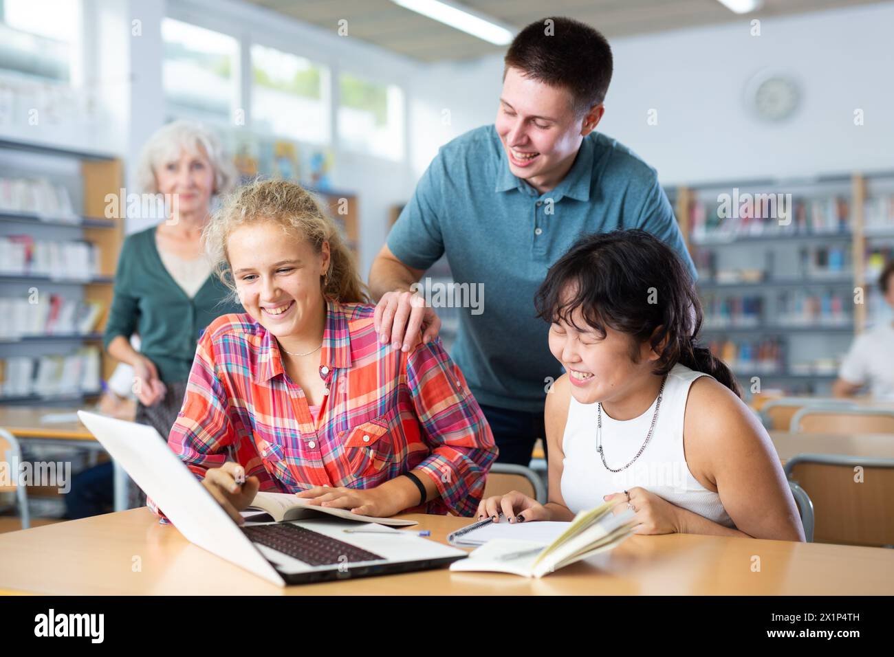 Schoolchildren help each other solve the task in school library Stock ...