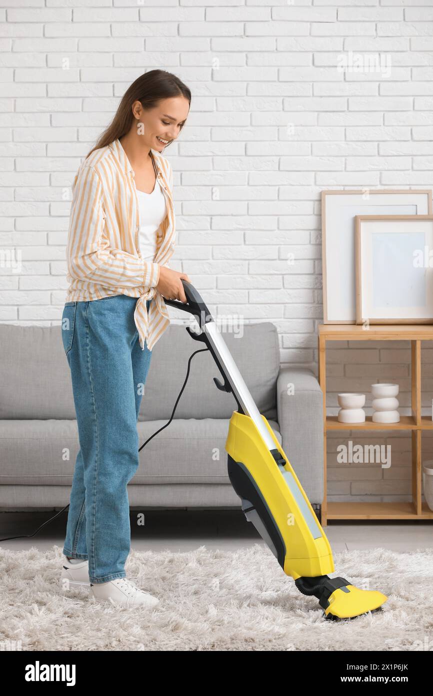Pretty young woman cleaning living room with vacuum cleaner Stock Photo - Alamy