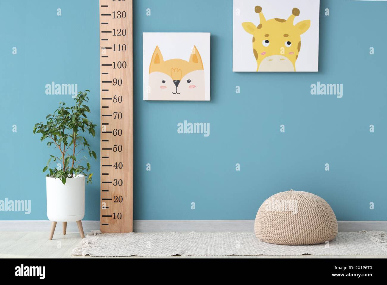 Wooden stadiometer with cute animal paintings and houseplant near blue ...