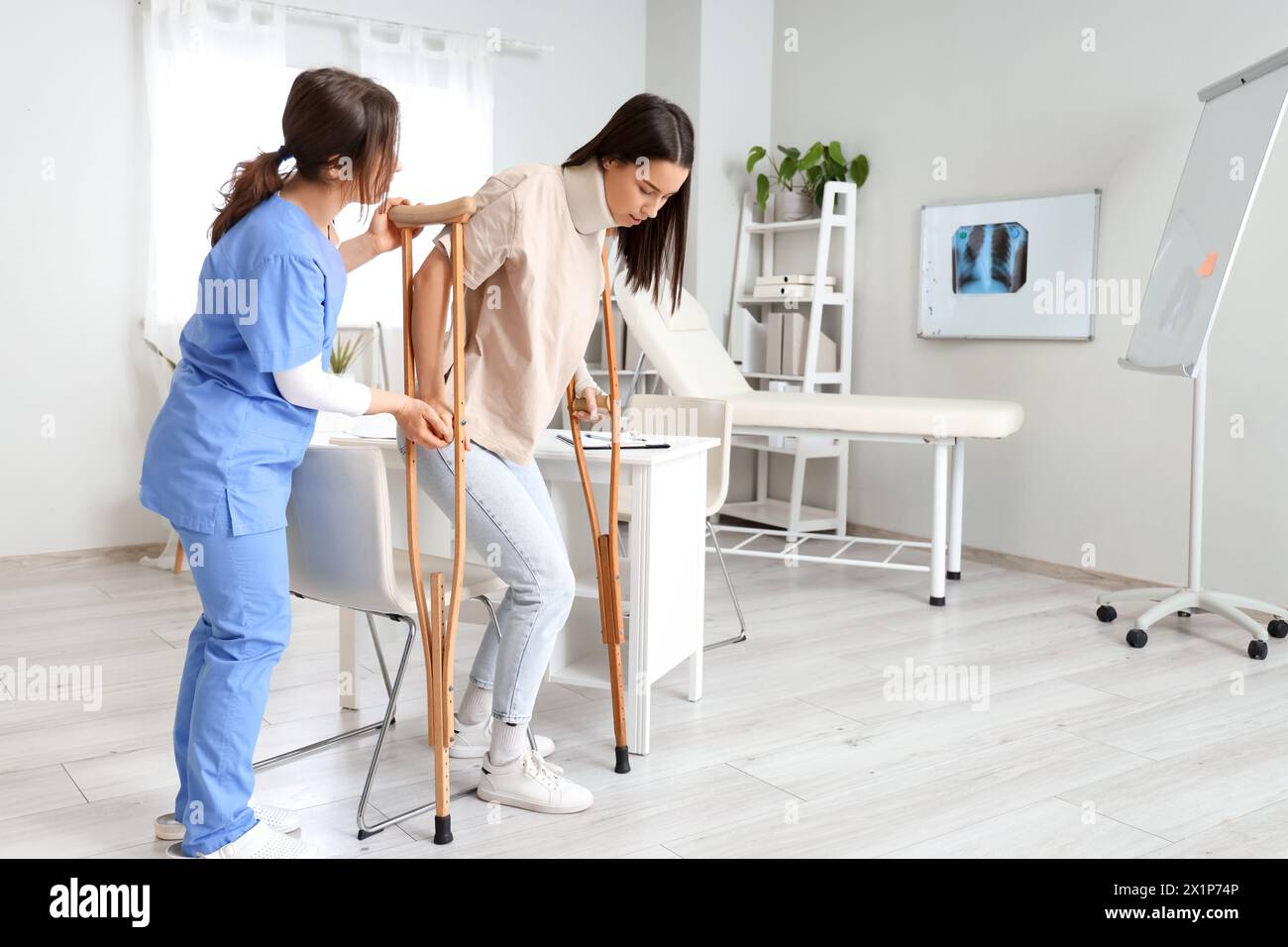 Injured young woman after accident with crutches standing up from chair ...