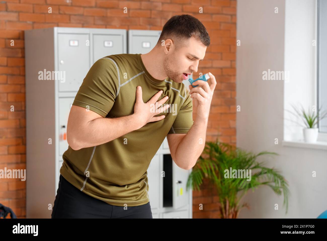 Sporty young man using inhaler in gym Stock Photo - Alamy