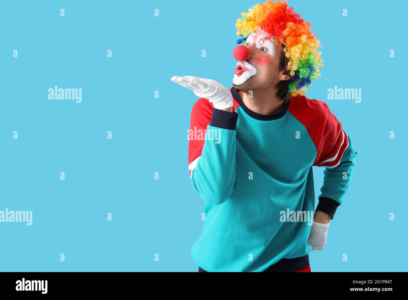 Portrait of clown blowing kiss on blue background. April Fool's day ...