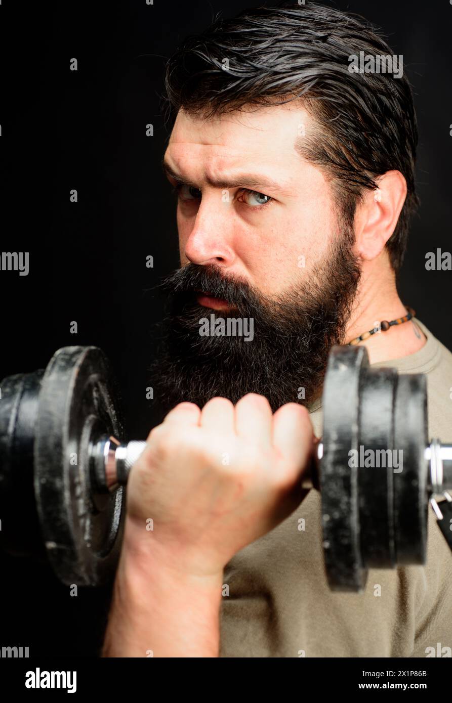Weightlifting and bodybuilding. Closeup portrait of bearded muscular sportsman lifting dumbbell ...
