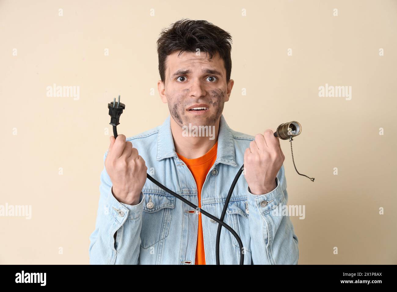 Electrocuted young man with burnt face and plug on beige background ...