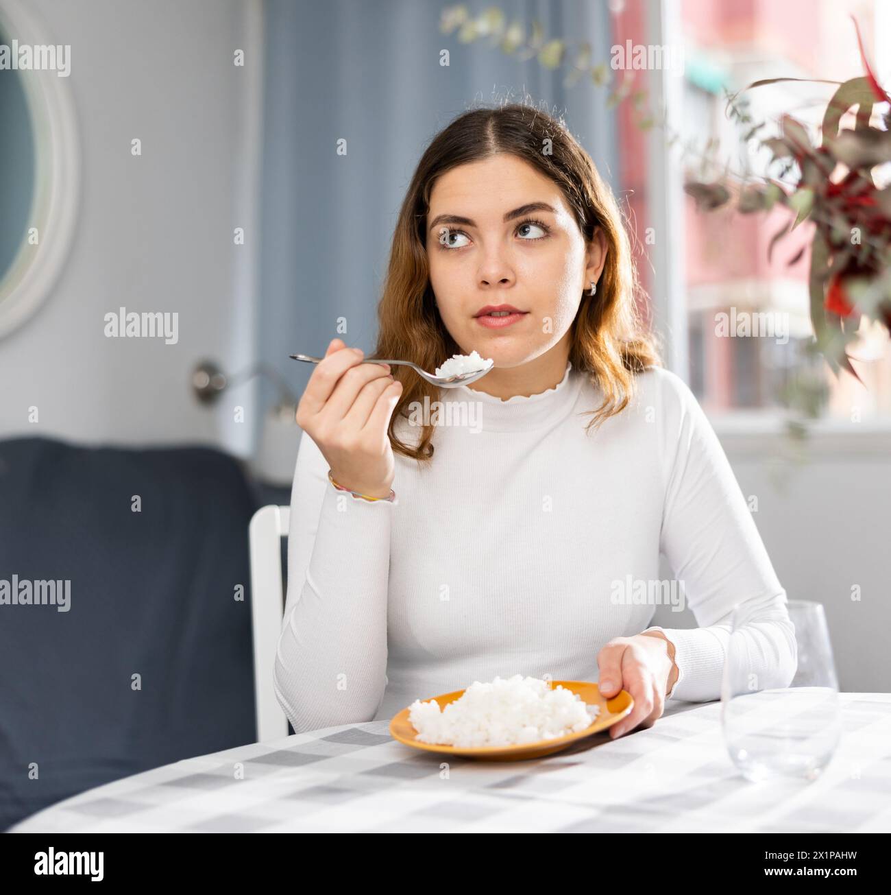 Emotional young woman eating rice at home Stock Photo - Alamy