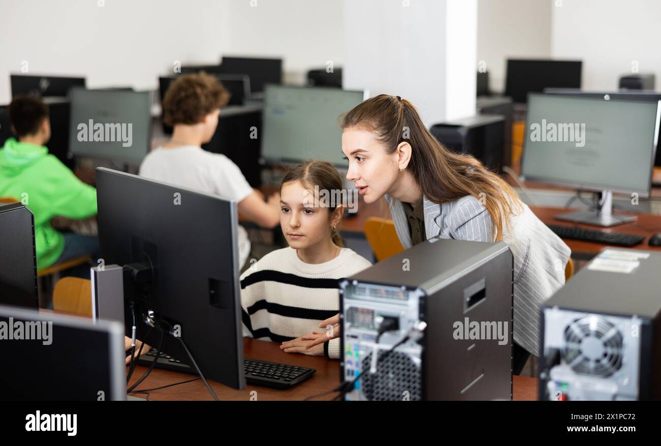 Female teacher and teenage girl looking at monitor of PC Stock Photo ...
