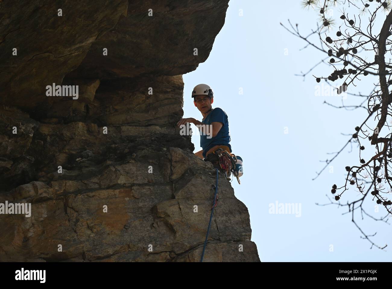 A male climber works his way up the cliff face at Pilot Mountain State ...
