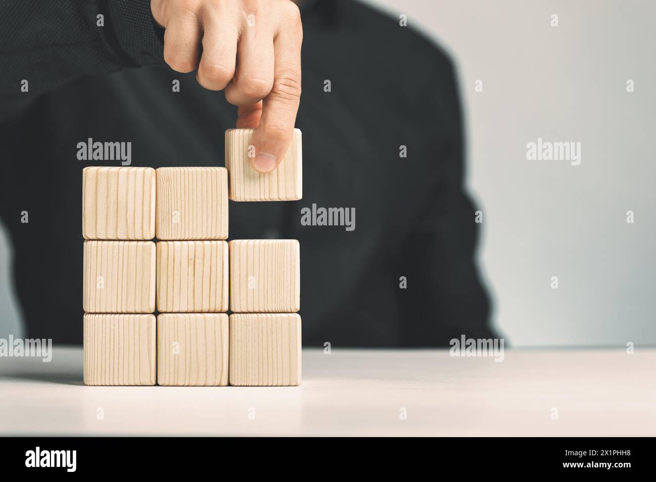 Hand putting and stacking blank wooden cubes on table with copy space ...