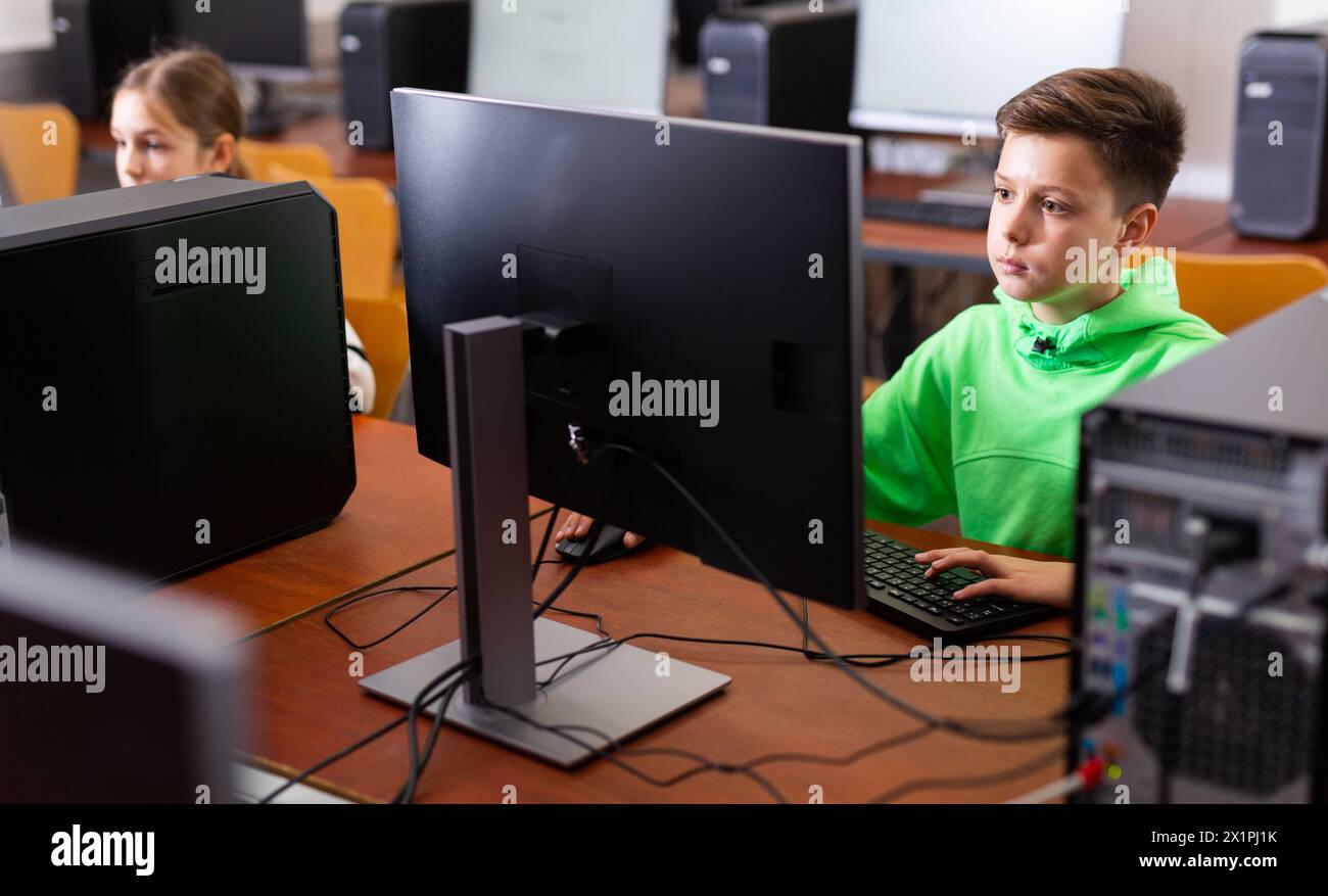 Focused tween boy studying with classmates in computer lab Stock Photo ...