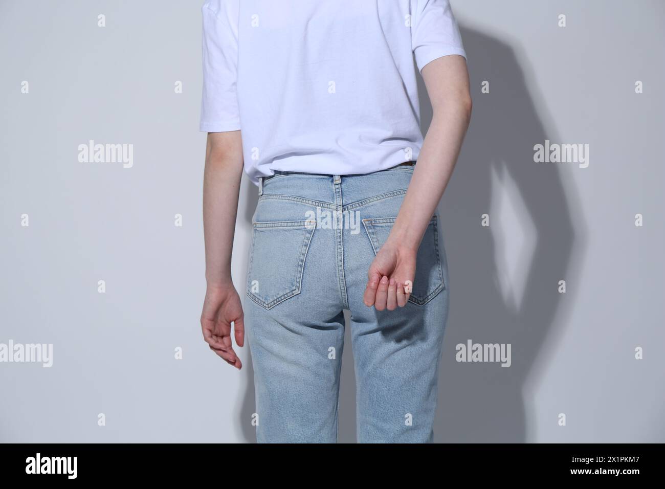 SOS gesture. Woman showing signal for help behind her back on light ...