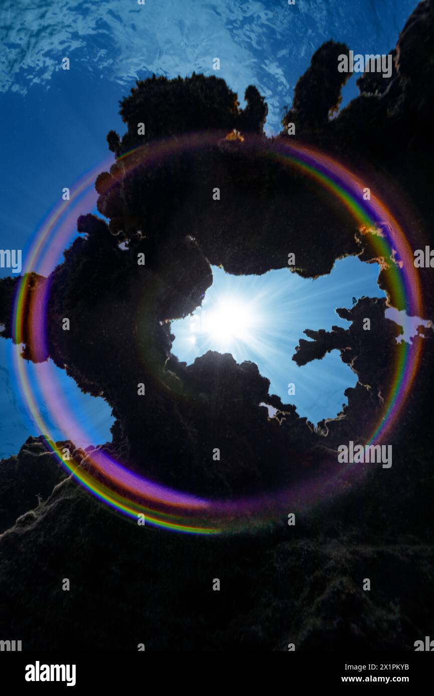 A circular rainbow is created underwater with sun rays through the ...