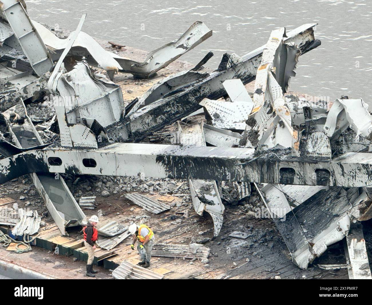 Salvors on a barge examine wreckage from the Francis Scott Key Bridge ...