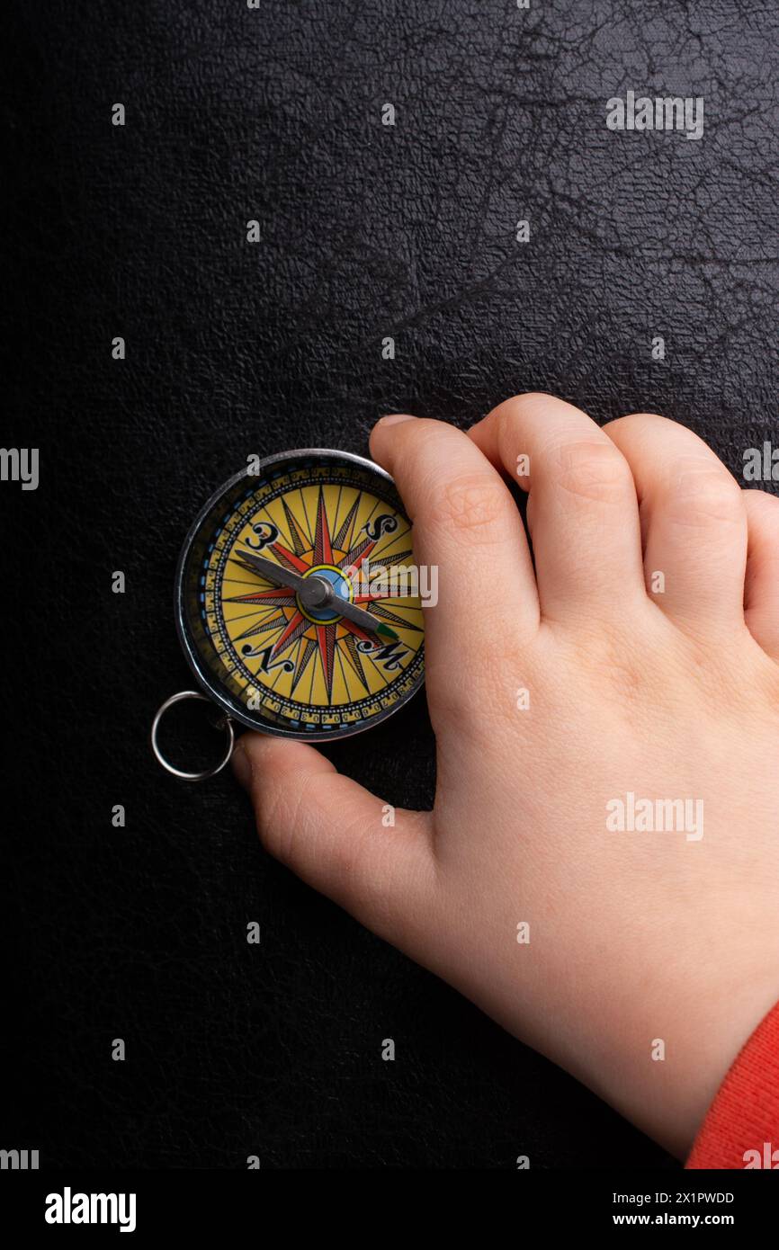 Hand is holding a magnetic compass on black background Stock Photo - Alamy