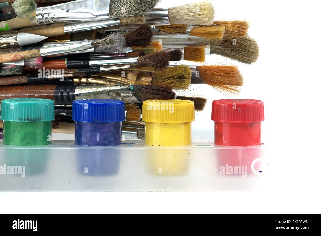 Array of paintbrushes of different sizes and colors alongside cans of ...