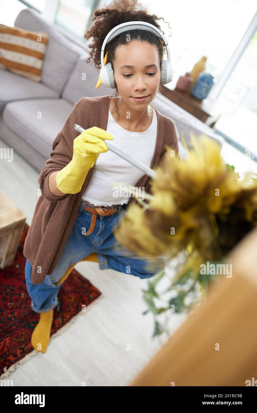 Home, duster and woman with headphones, cleaning furniture surface and ...