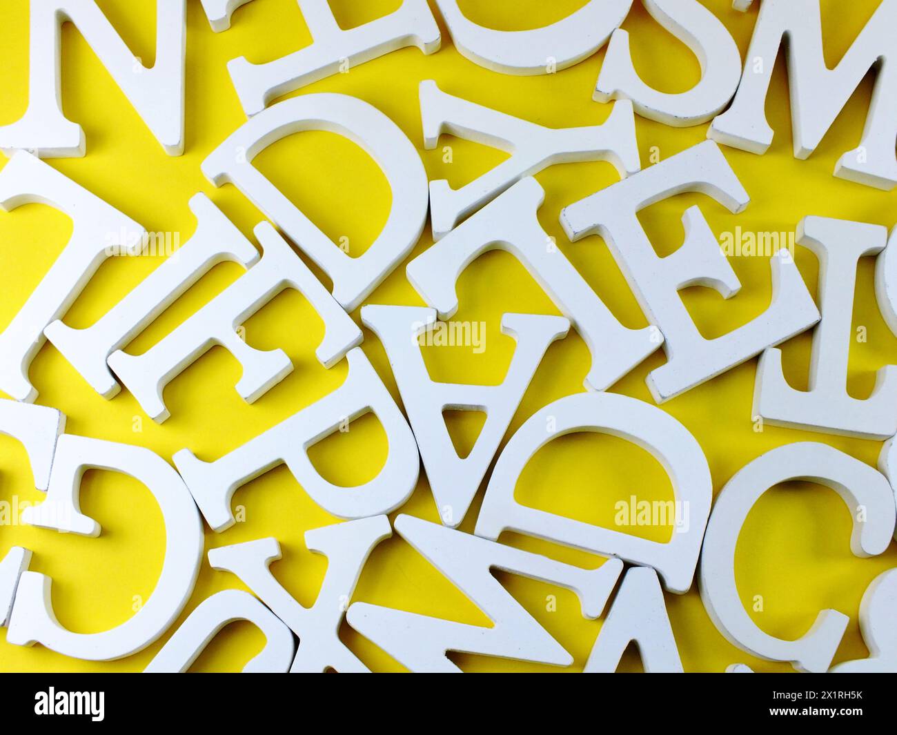 random white wooden alphabet letters top view on yellow background ...