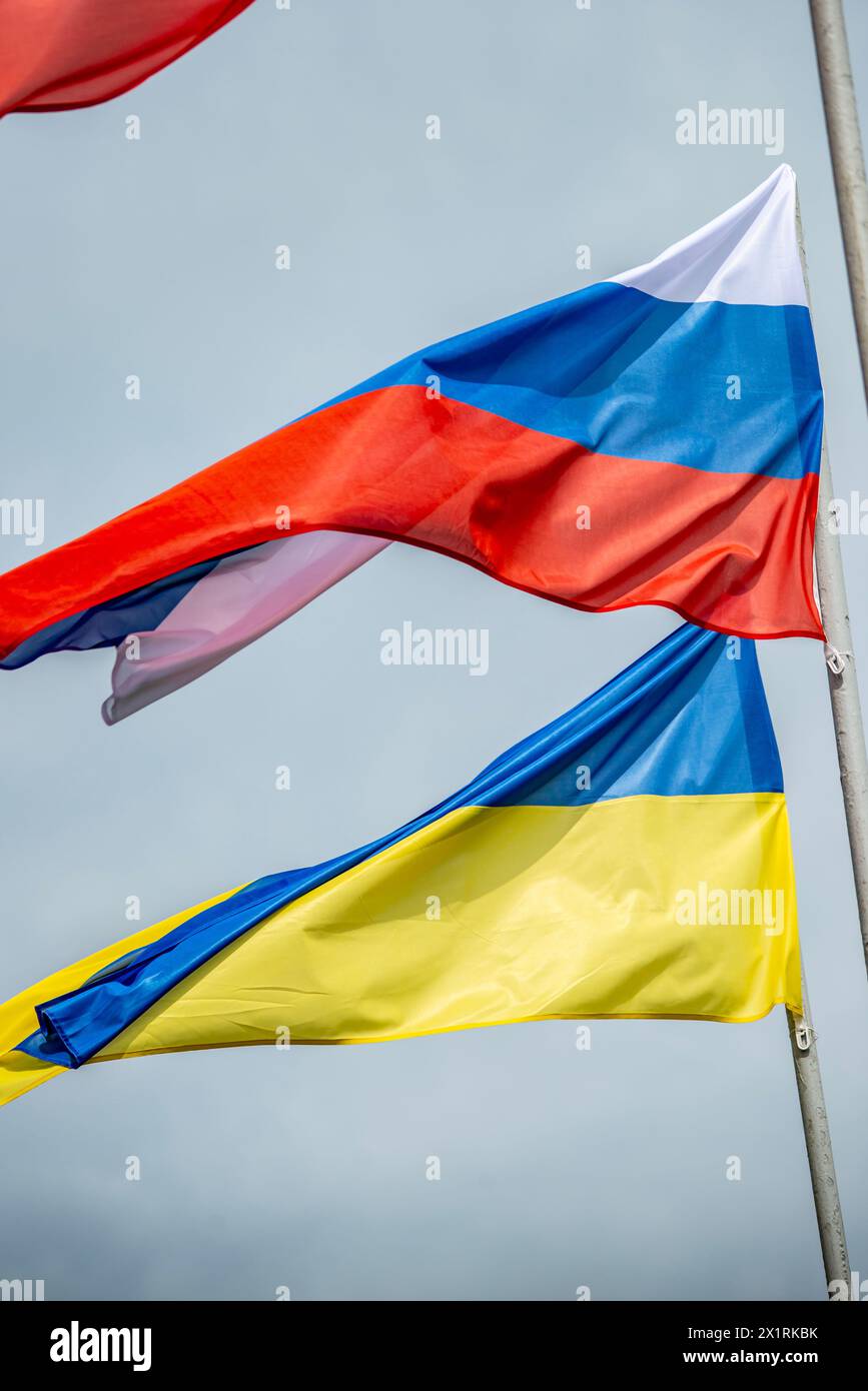 Russian and Ukrainian flags are waving with wind over blue sky. Low ...