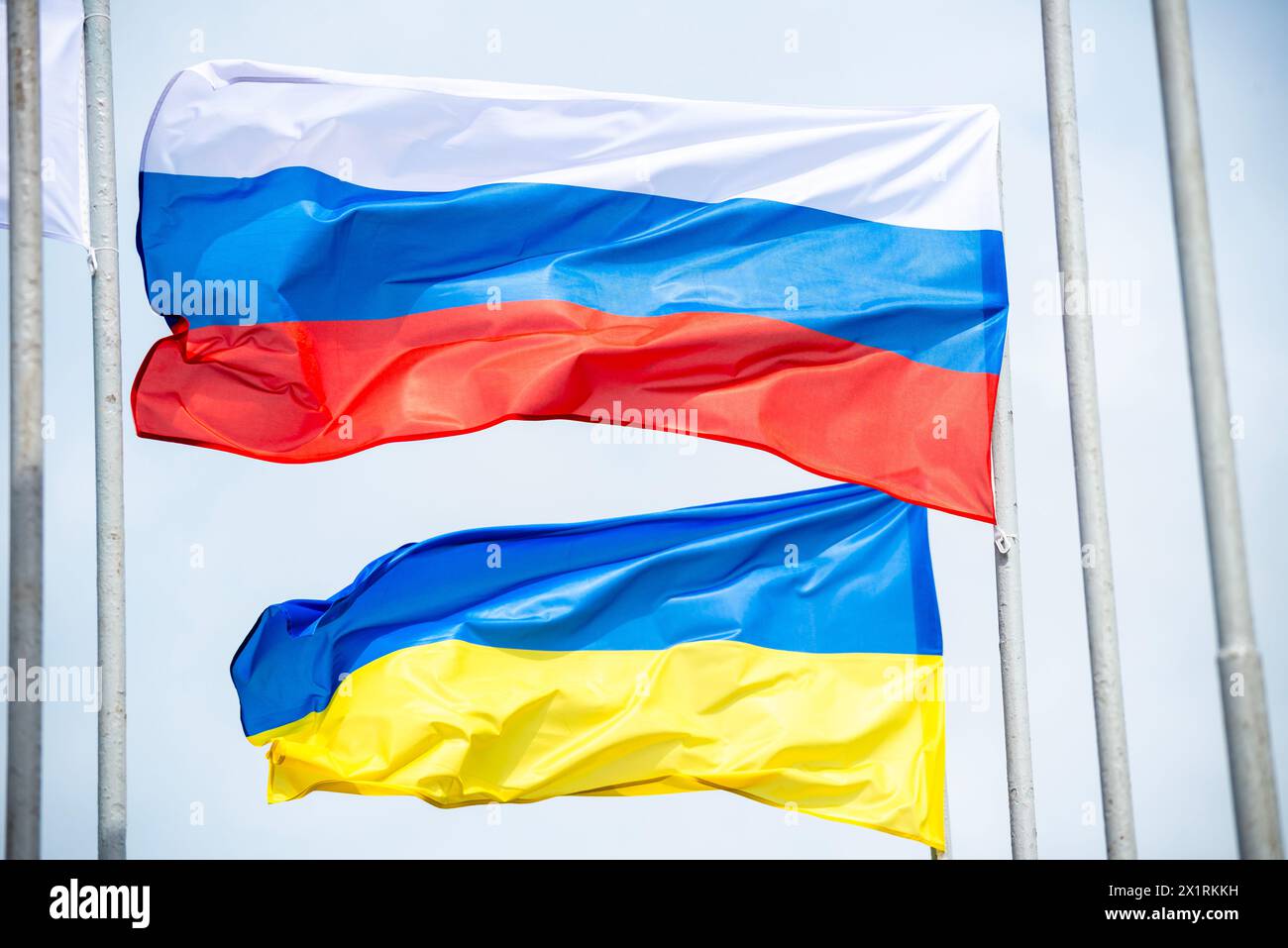 Russian and Ukrainian flags are waving with wind over blue sky. Low ...