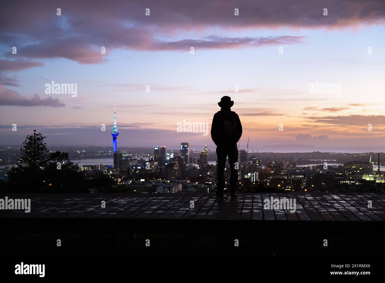Man in silhouette looking at the views of Sky Tower and cityscape. Mt ...