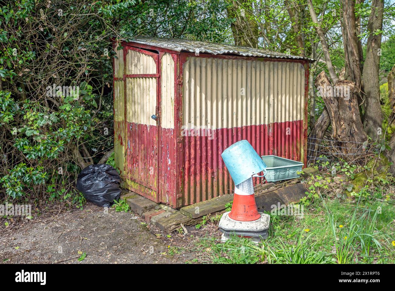 Old dilapidated corrugated panel shed in disrepair surrounded my over ...
