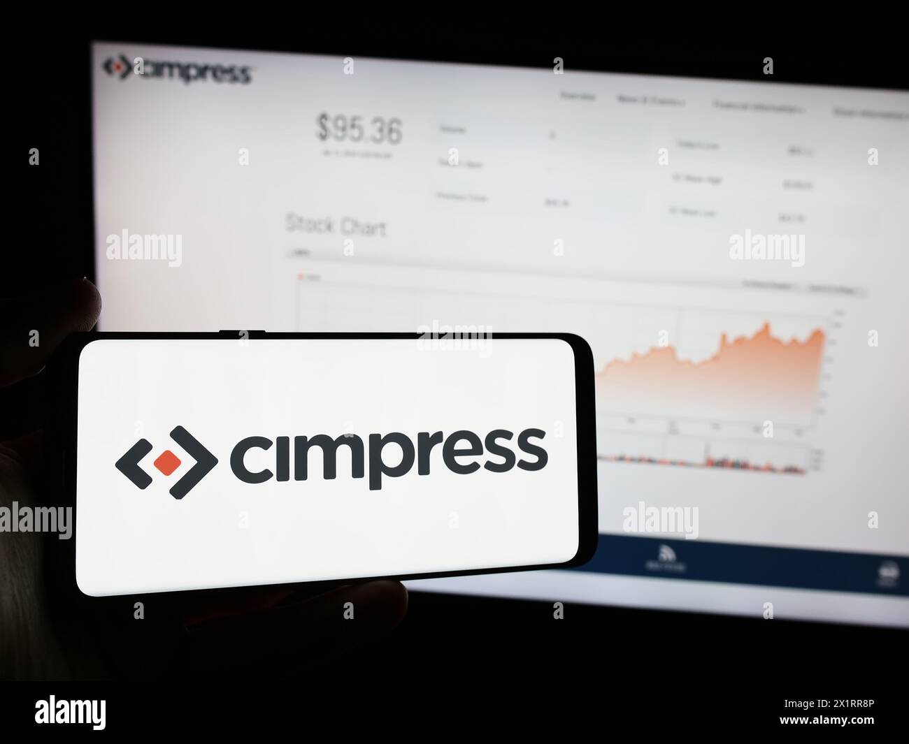 Person holding mobile phone with logo of mass customization company Cimpress plc in front of ...