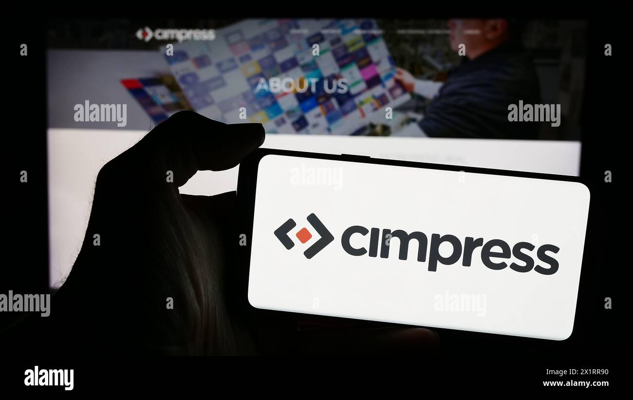 Person holding smartphone with logo of mass customization company Cimpress plc in front of ...