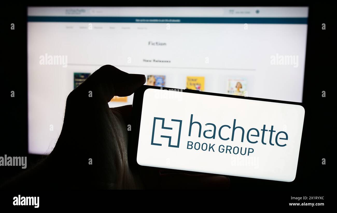 Person holding mobile phone with logo of American publishing company ...