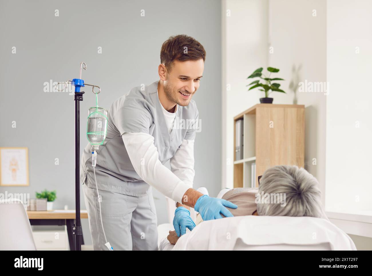Young nurse taking care of senior patient who is lying on bed and ...