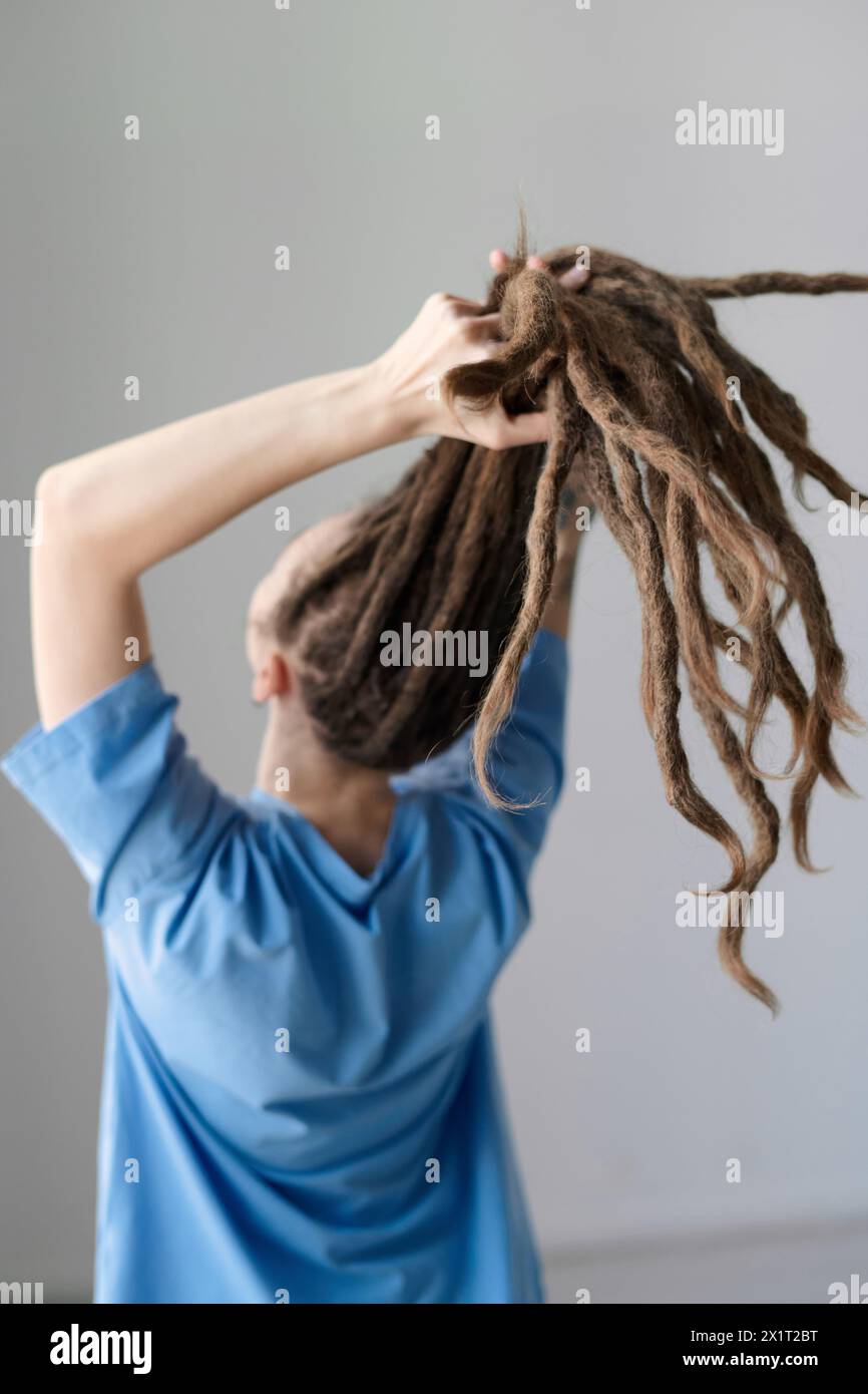 Vertical back view of Caucasian woman holding long dreadlocks out to ...