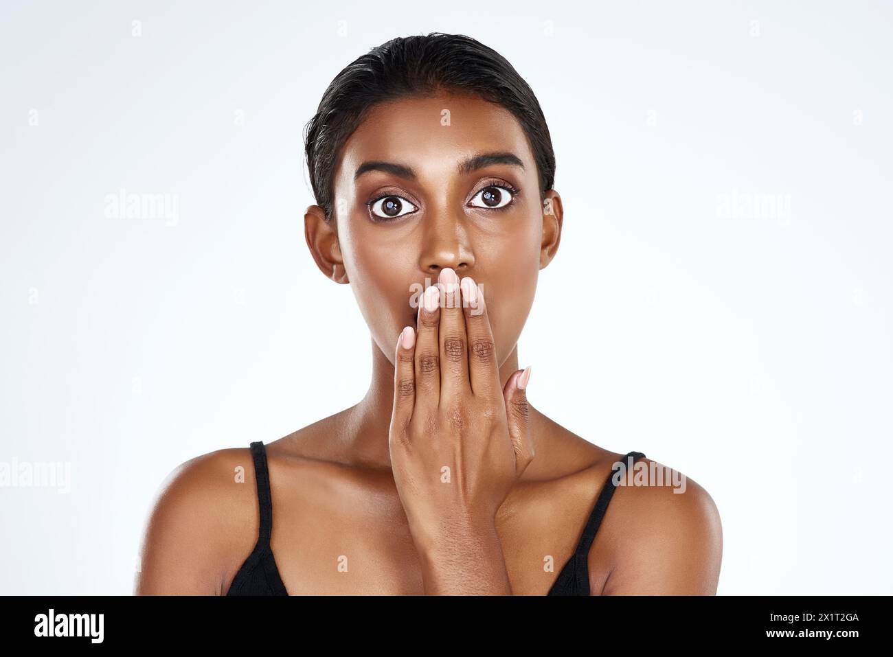 Surprise, portrait and Indian woman with hand to cover shock with beauty in studio background or ...