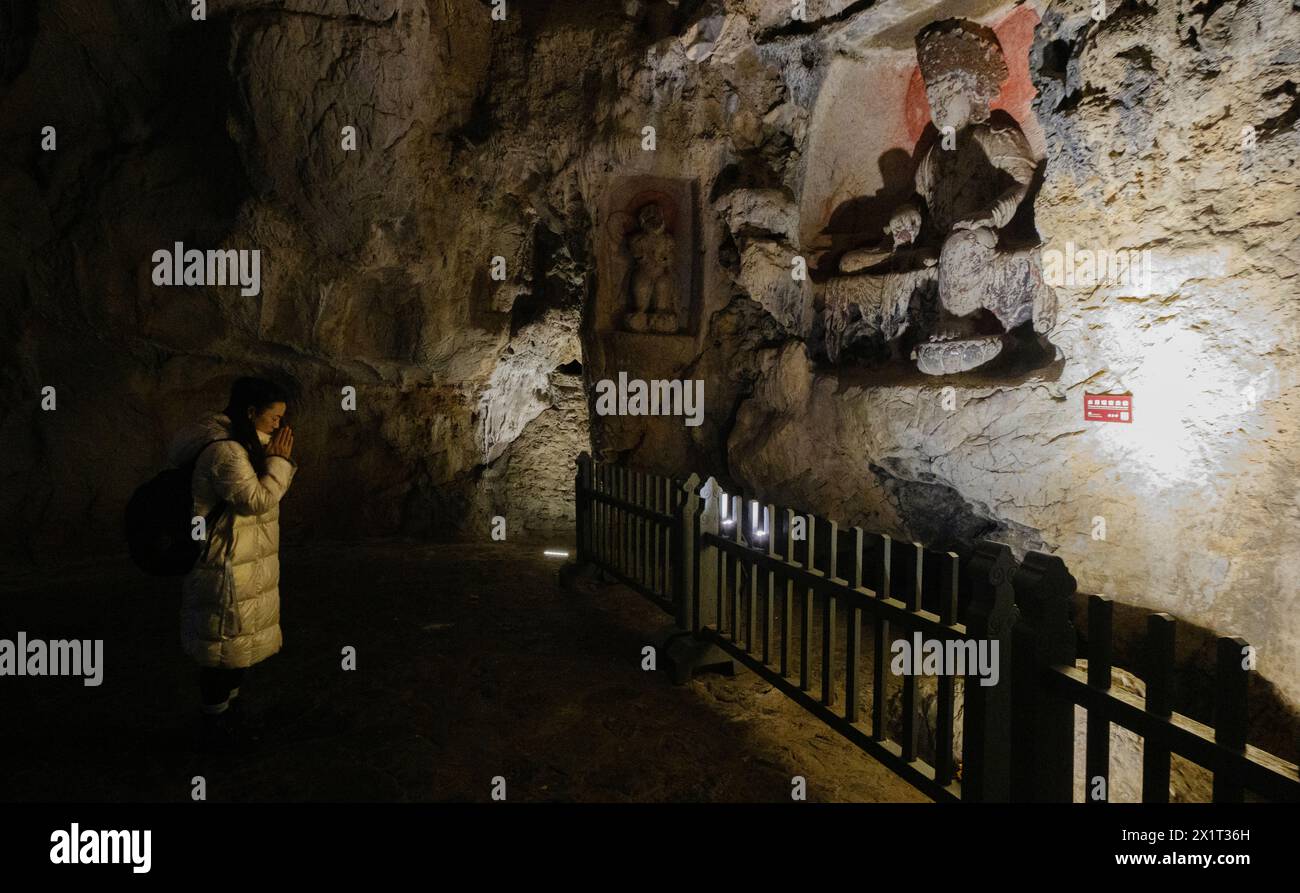 A woman prays to a Buddha statue at a grotto at the Lingyin Fei Lai Feng temples complex in ...