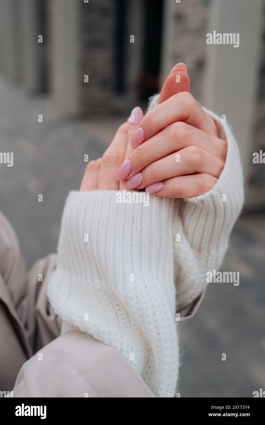 Fashion details of a knitted white sweater sleeves, female hands with ...