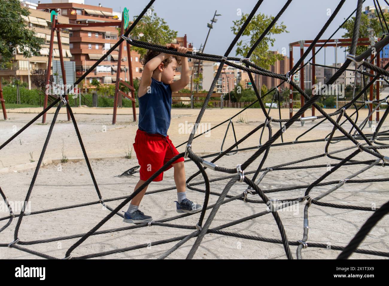 Boy Navigating Through Rope Climbing Frame Stock Photo - Alamy