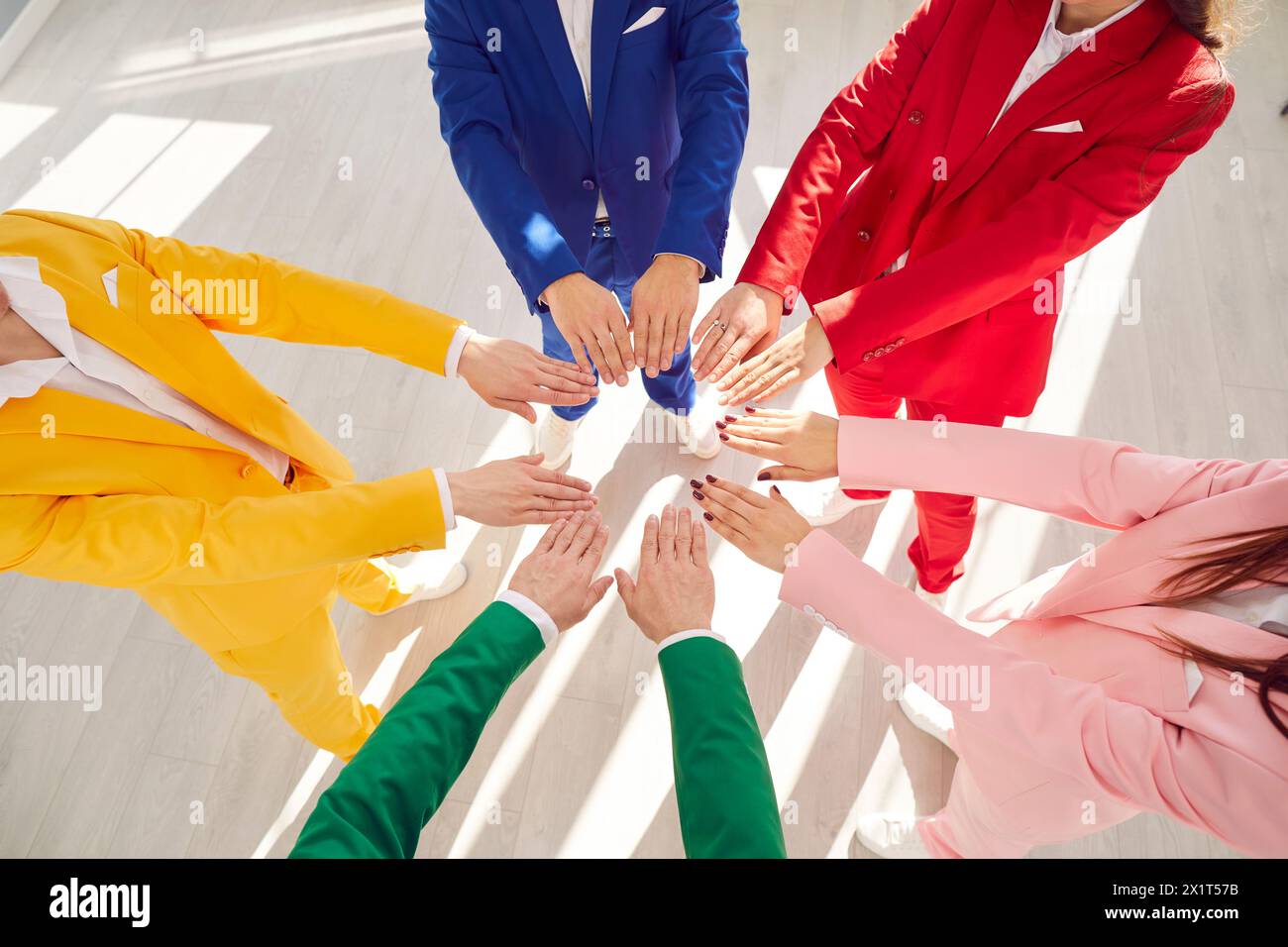 Dressed in colorful fashionable business suits team joins hands to ...