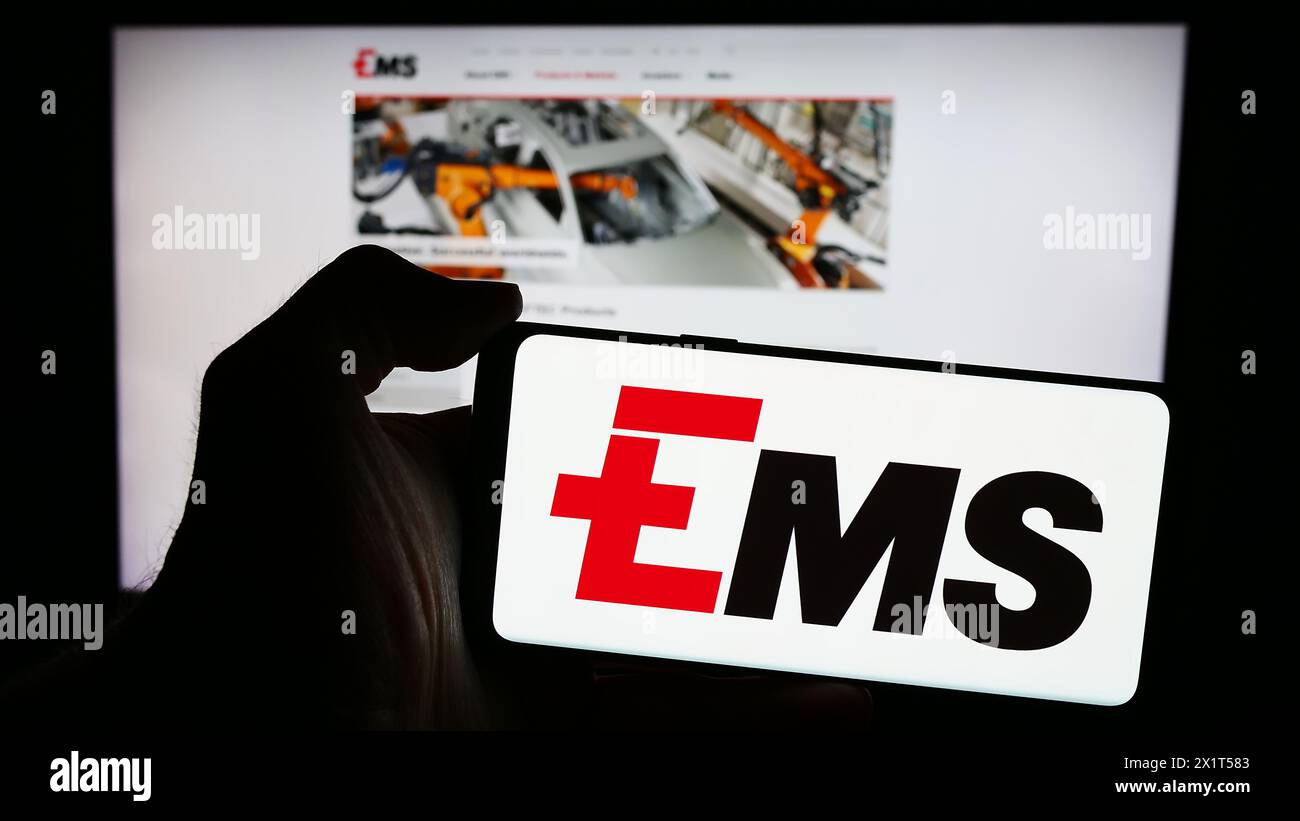 Person holding mobile phone with logo of Swiss chemicals company Ems ...