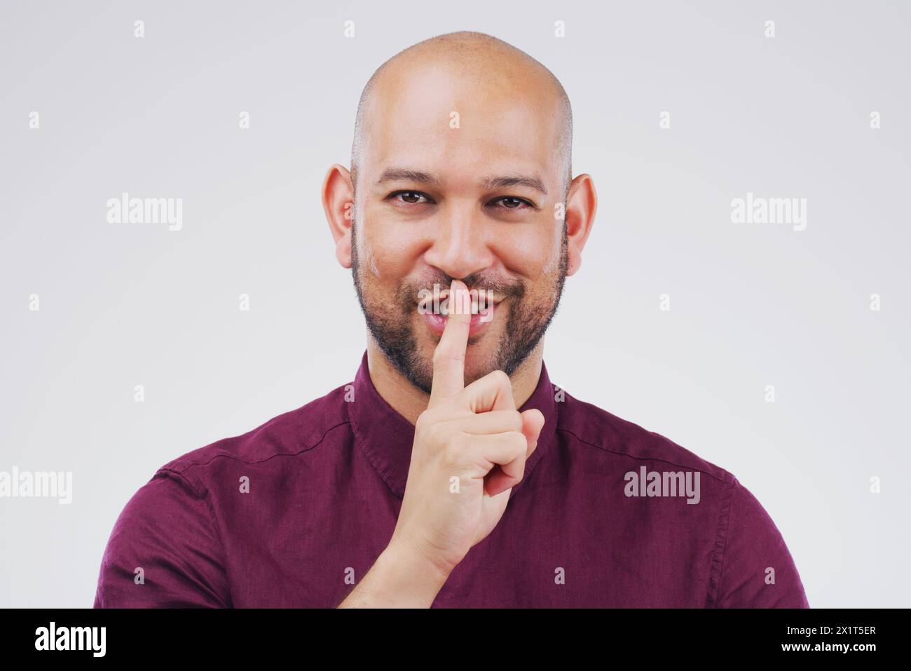 Portrait, smile and shush with secret man in studio isolated on gray ...