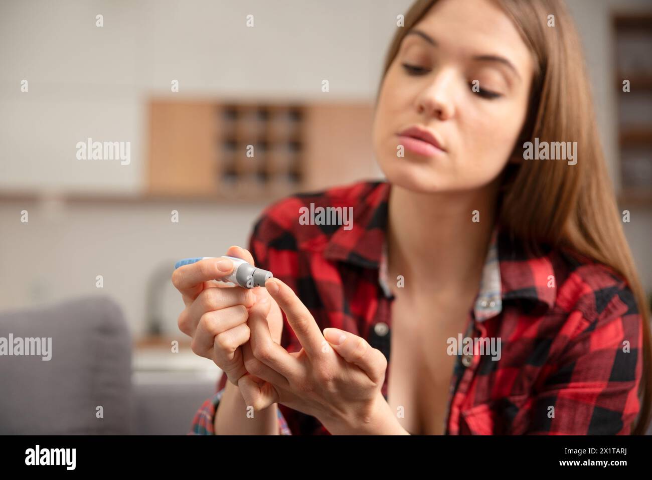 Woman using a glucose monitor to manage her diabetes at home Stock ...