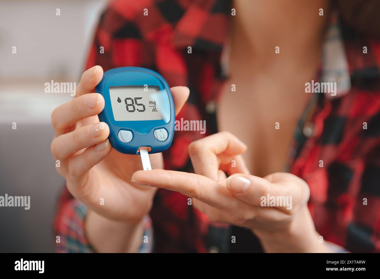 Woman using a glucose monitor to manage her diabetes at home Stock ...