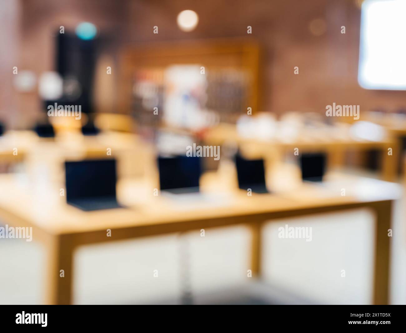 Softly focused silhouettes of laptops on wooden tables in an unbranded ...