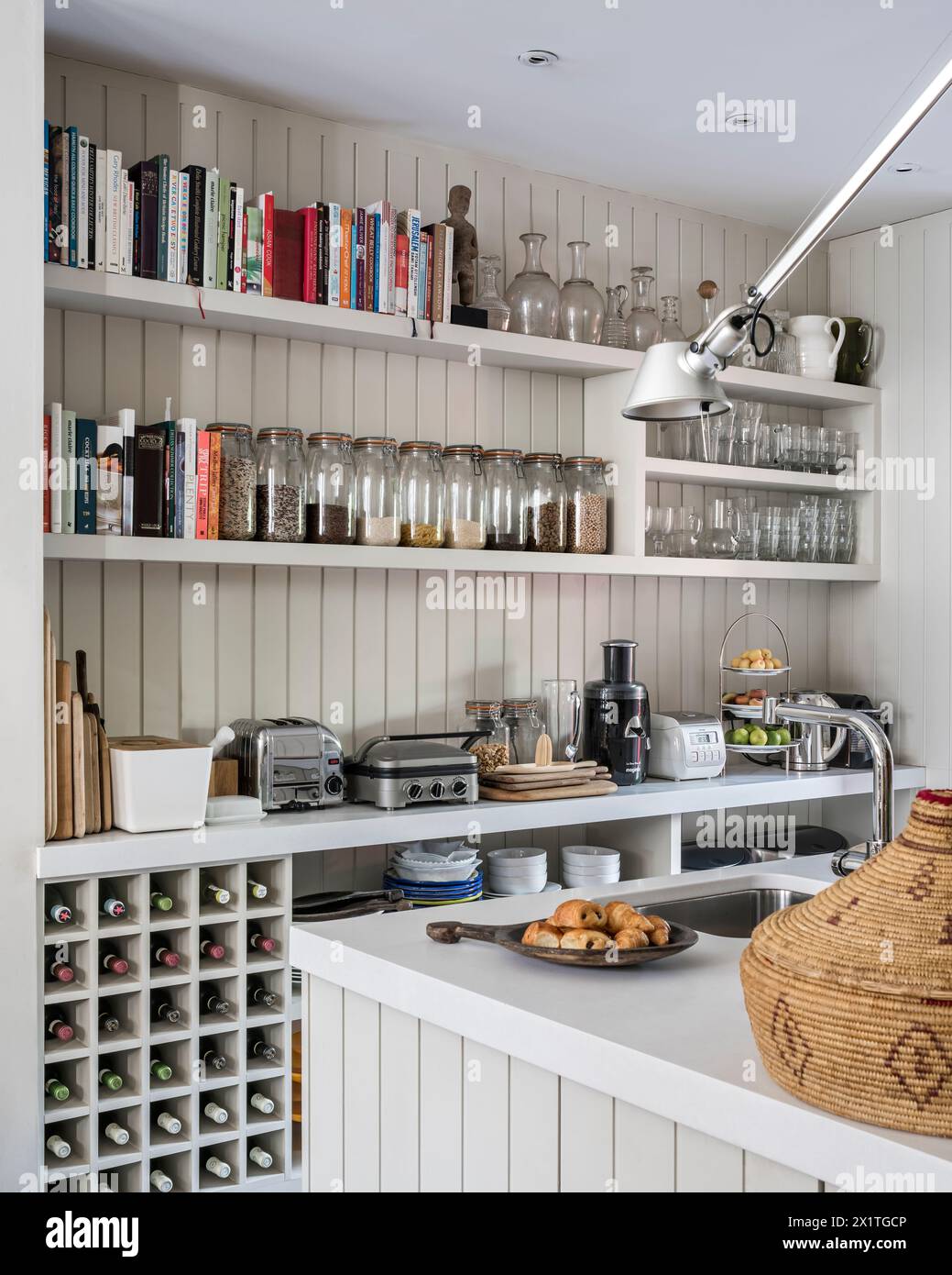 Storage jars and wine bottles ordered on kitchen shelves in Chelsea ...