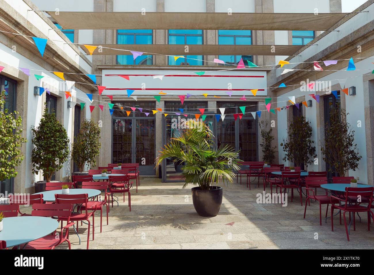 A courtyard, red chairs, and a large potted plant decorated for summer ...