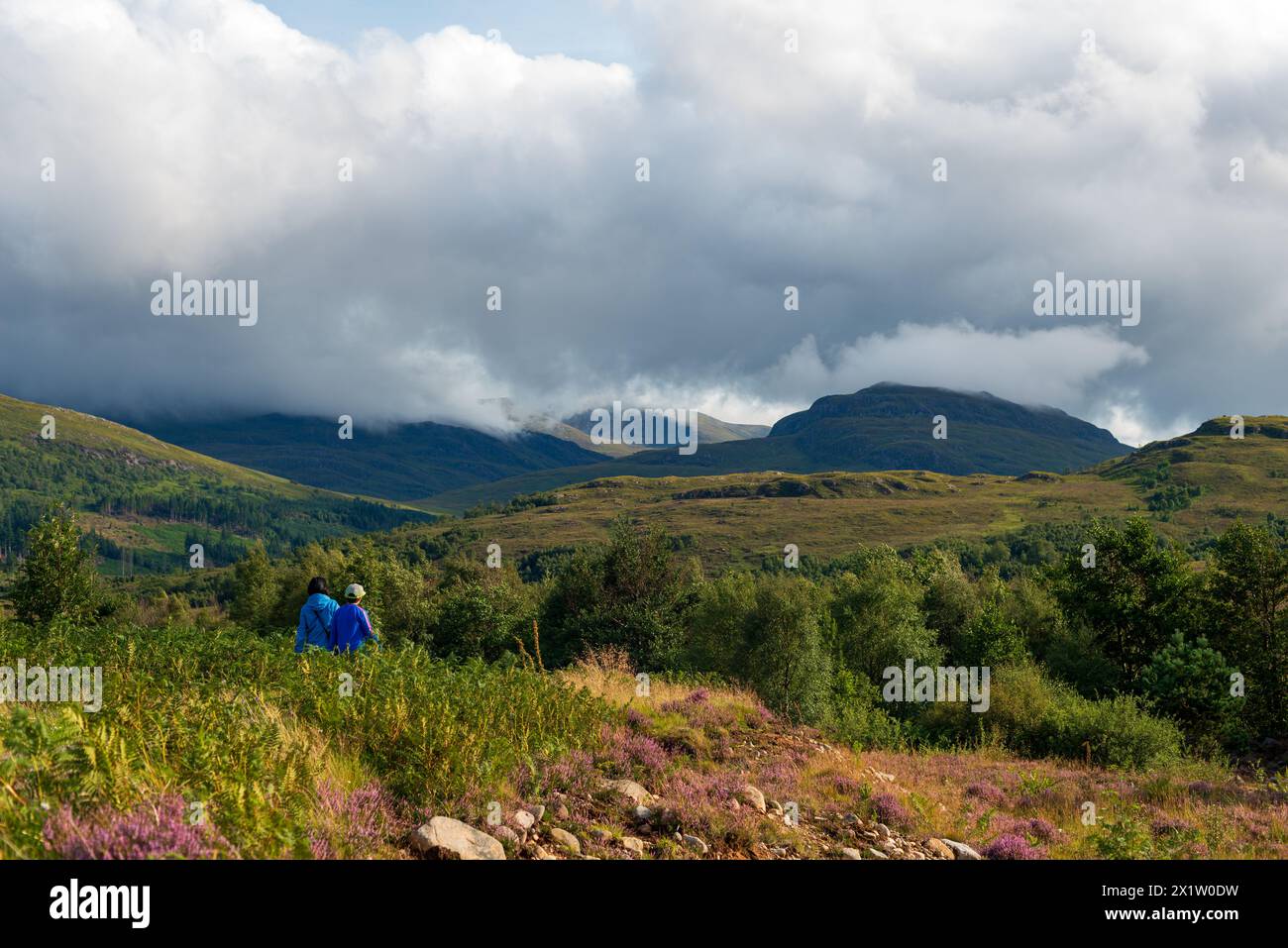 View of people walking through the scottish highlands Stock Photo - Alamy