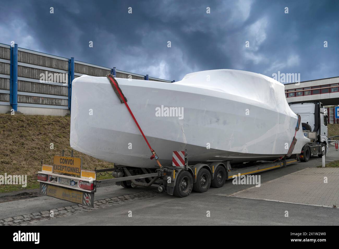 Heavy goods vehicle loaded with a motor yacht in a car park ...