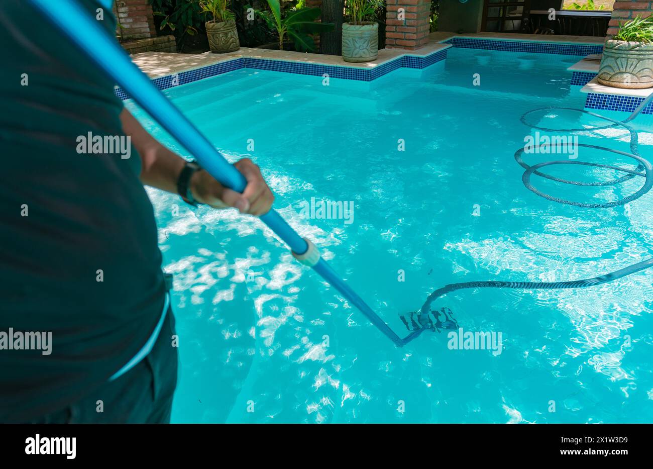 Man cleaning swimming pool with suction hose. Person cleaning a ...