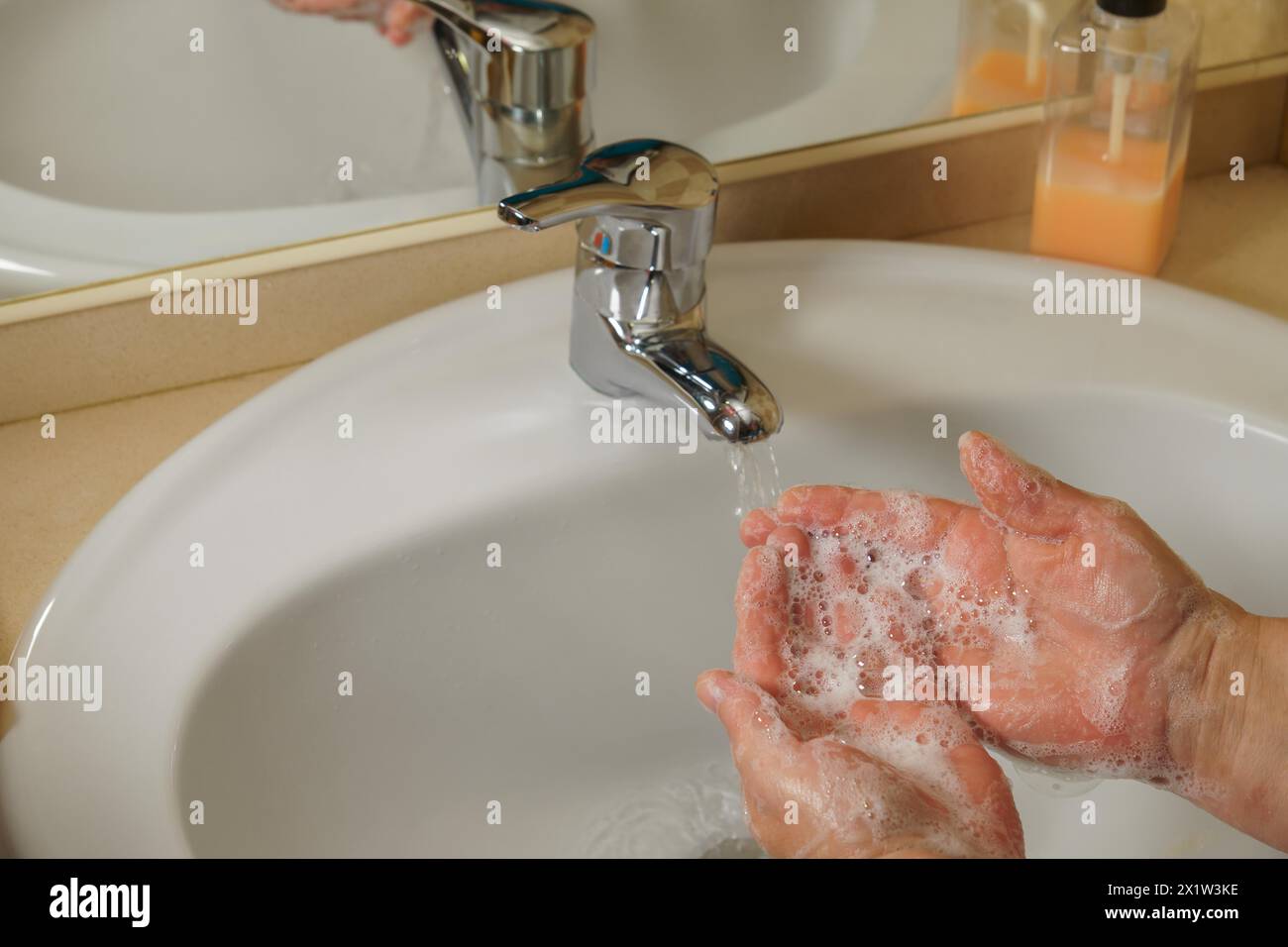 A woman washes her hands under the faucet. A stream of drinking water ...