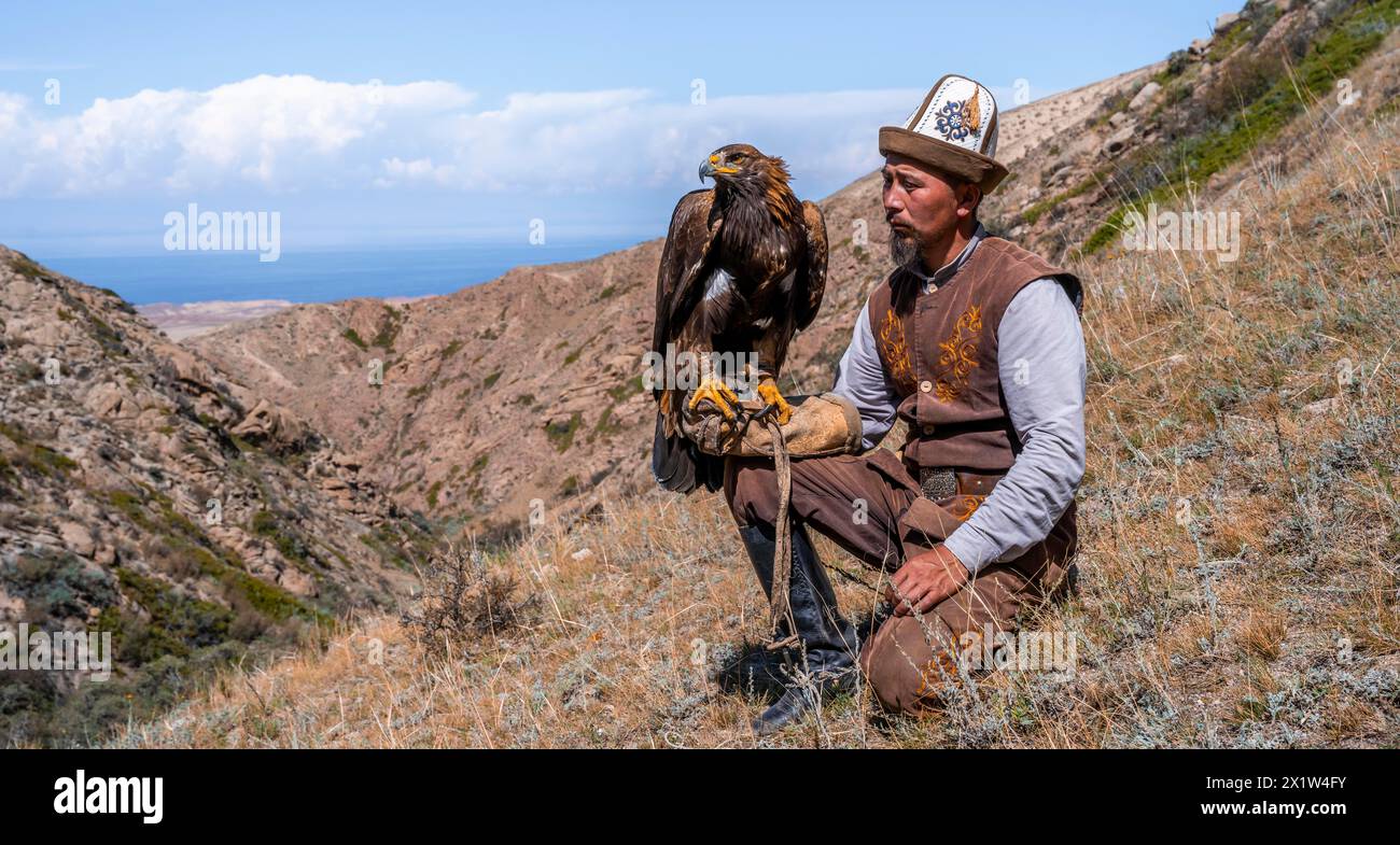 Traditional Kyrgyz eagle hunter with eagle in the mountains, hunting ...