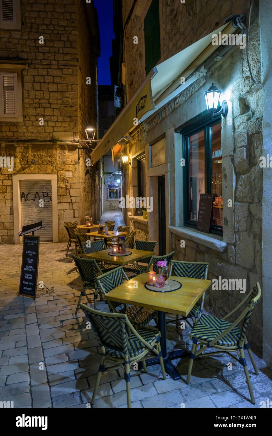 Empty cafe with tables on a cobblestone path at night, Trogir, Dalmatia ...
