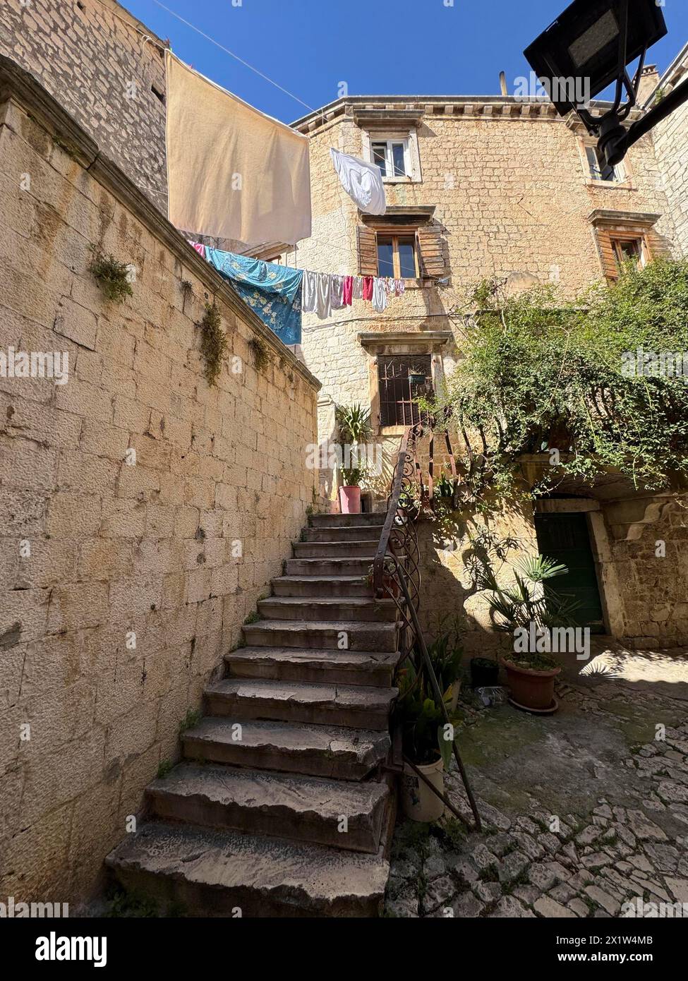 Stone staircase in a sunny alleyway of the old town centre with hanging ...