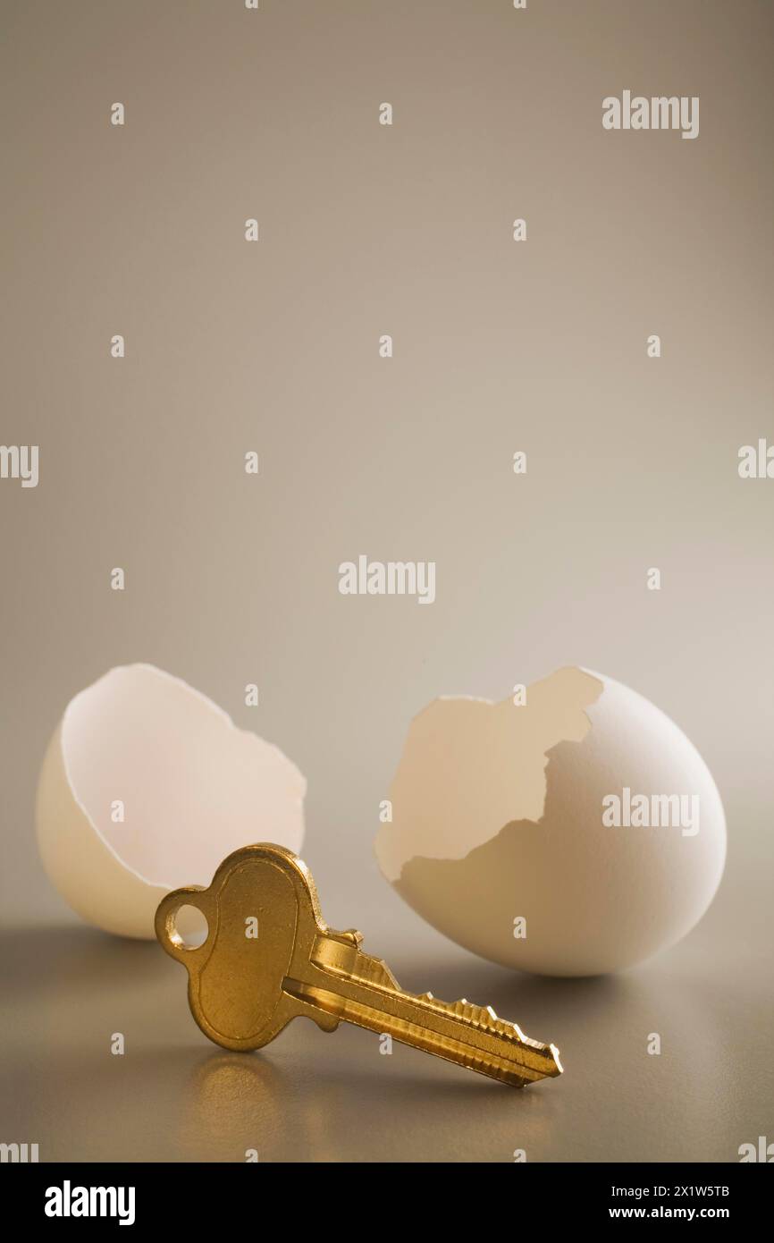 Close-up of antique brass key and two white cracked opened chicken egg ...